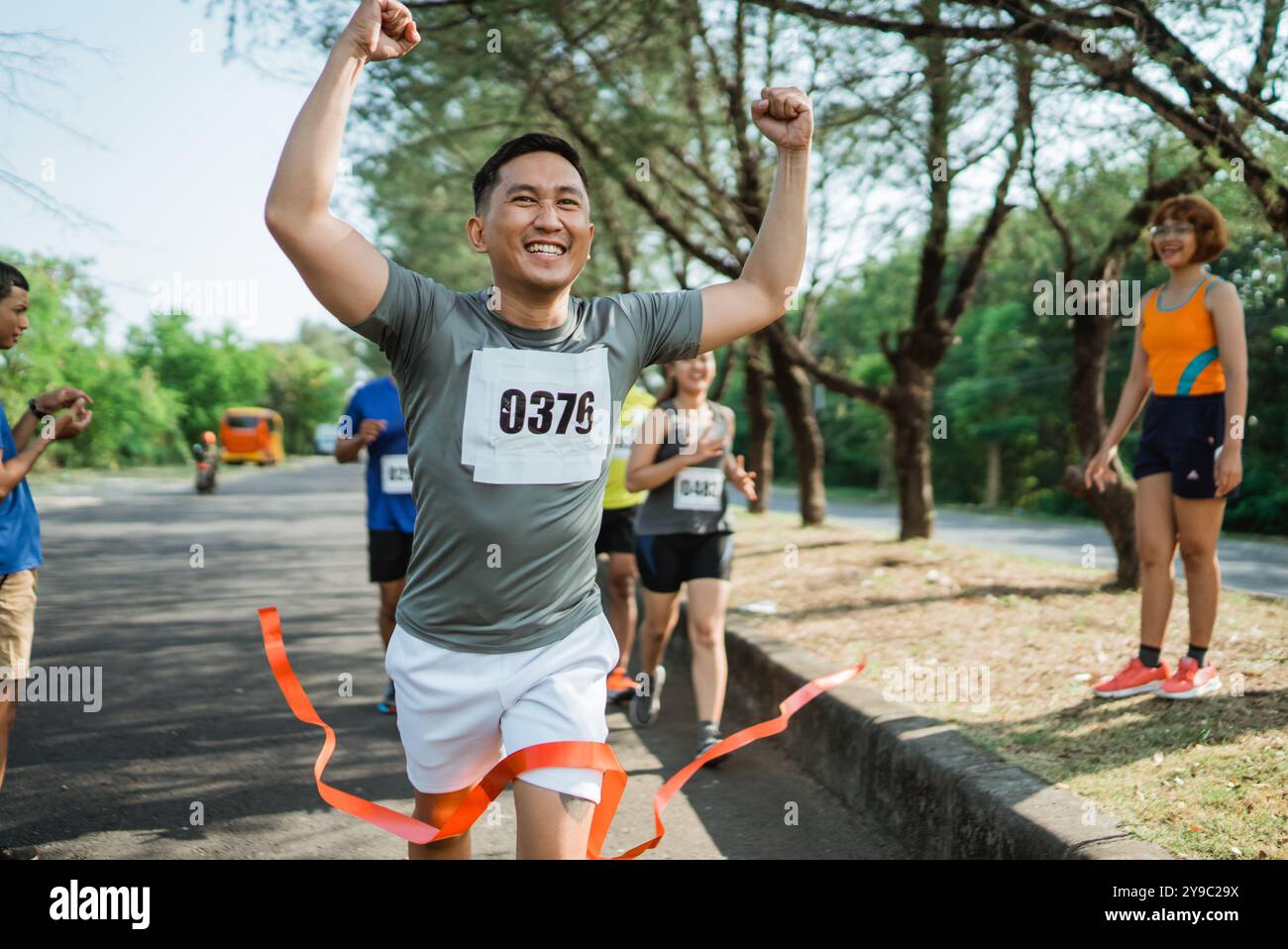 asian male runner crossing finish line Stock Photo - Alamy