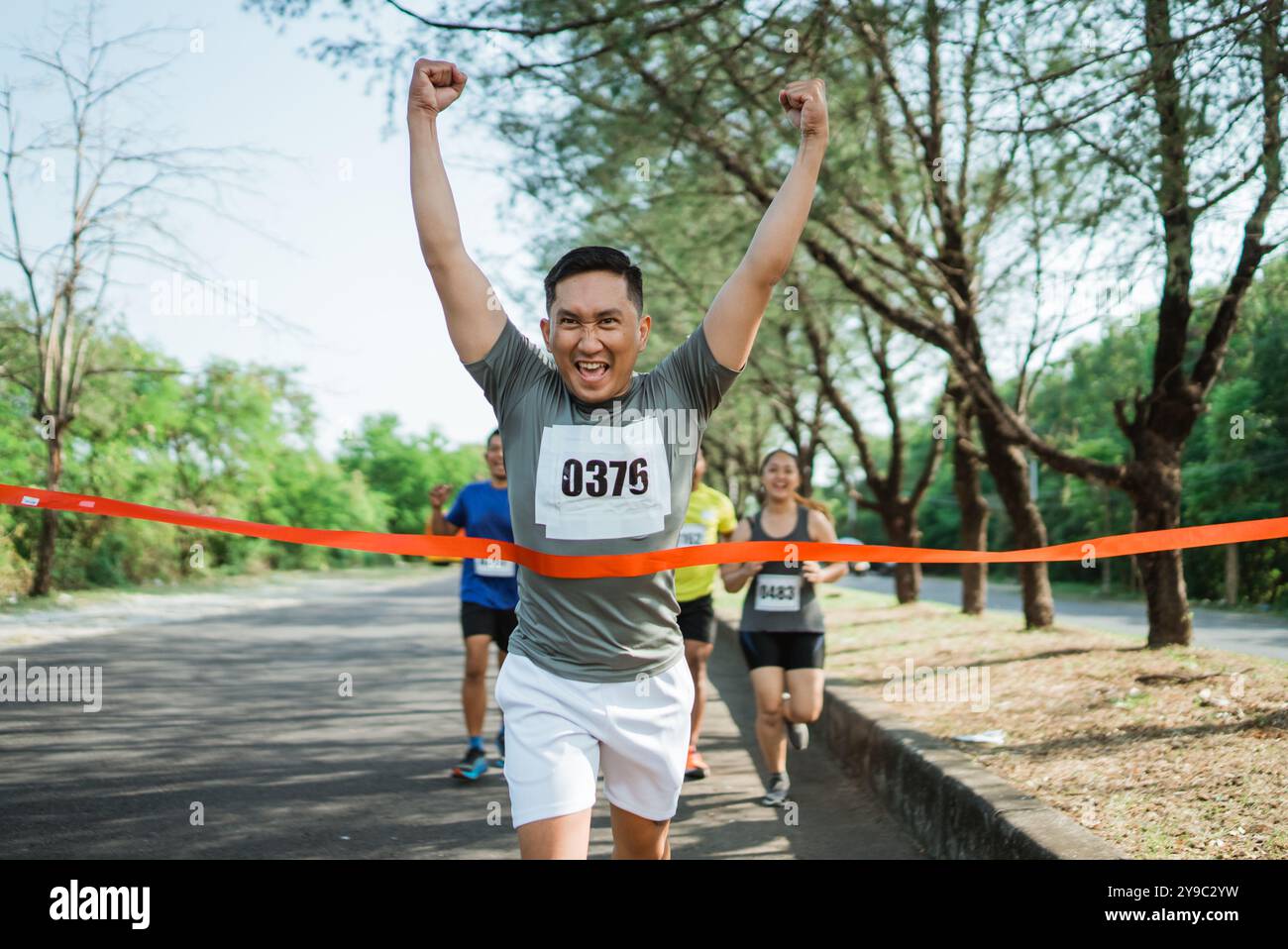 asian male runner crossing finish line Stock Photo - Alamy