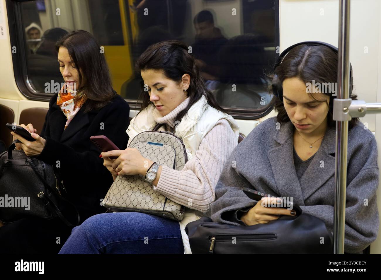 Passengers in a metro train at autumn, girls using smartphones in ...