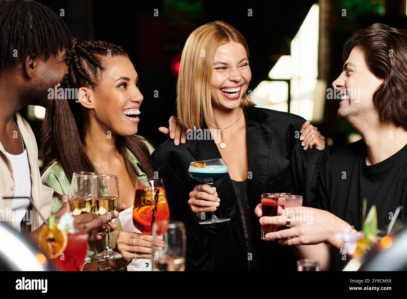 A group of young colleagues laughs and shares drinks during a fun ...