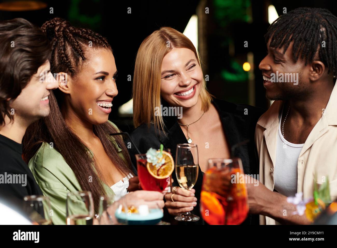 A group of joyful colleagues share drinks and laughter during a ...