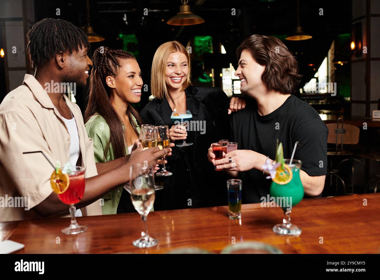 A group of young professionals celebrates together, sharing drinks and ...