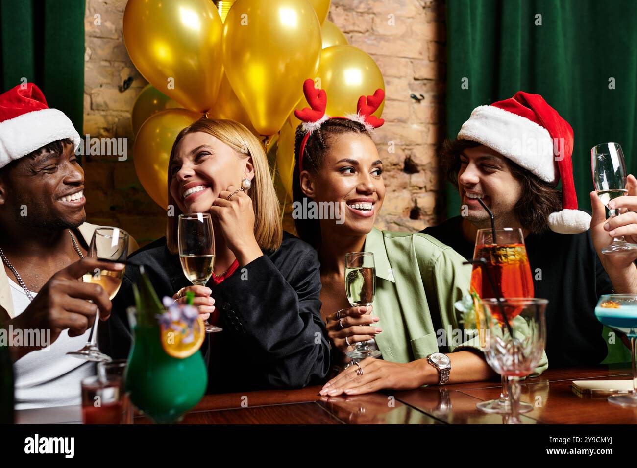 A group of young diverse colleagues enjoys festive drinks and laughter ...