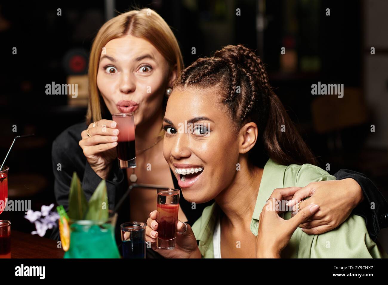 Two cheerful colleagues clink their drinks together, enjoying a fun ...