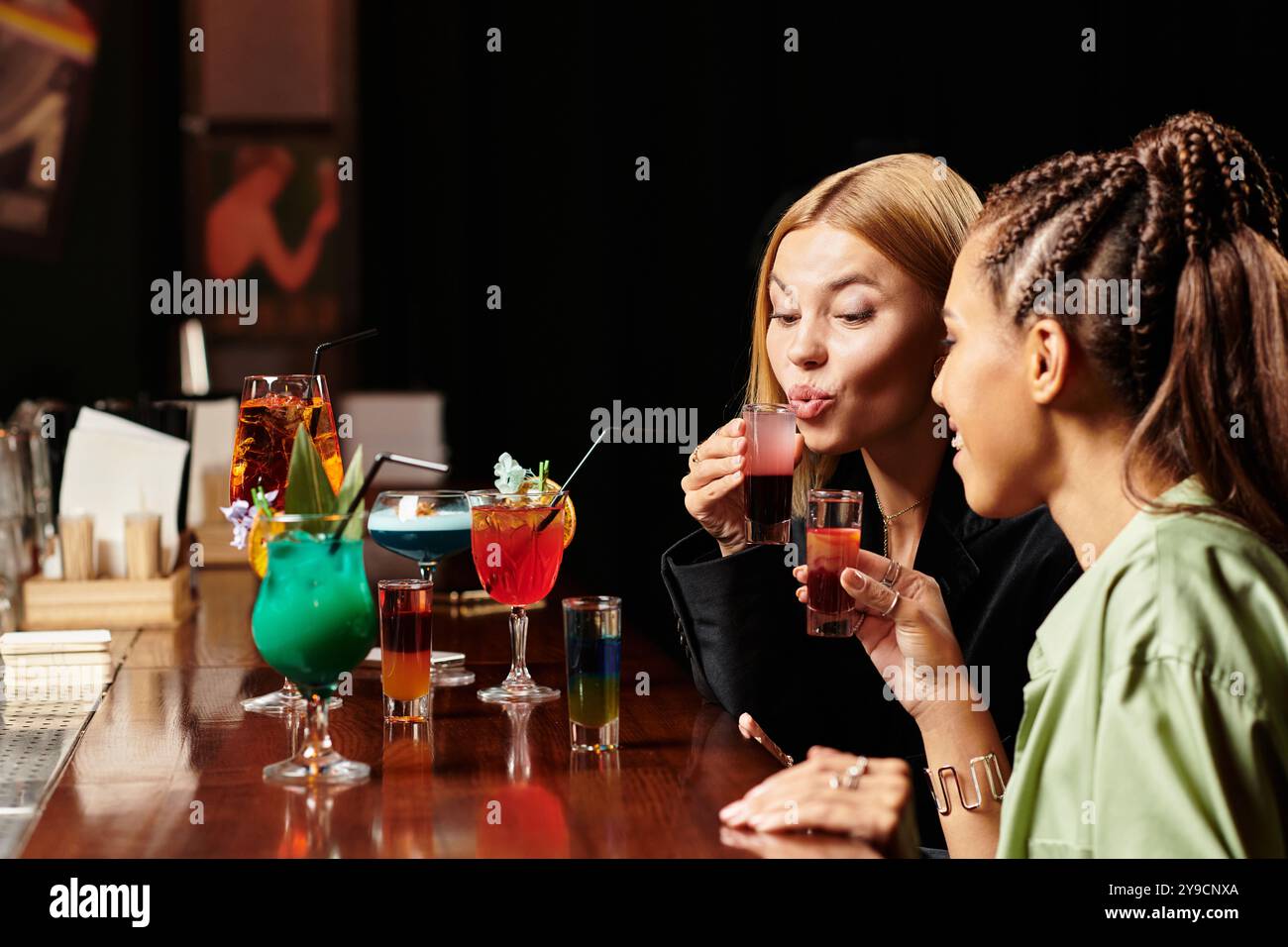 Young colleagues laugh and sip vibrant cocktails, celebrating teamwork ...