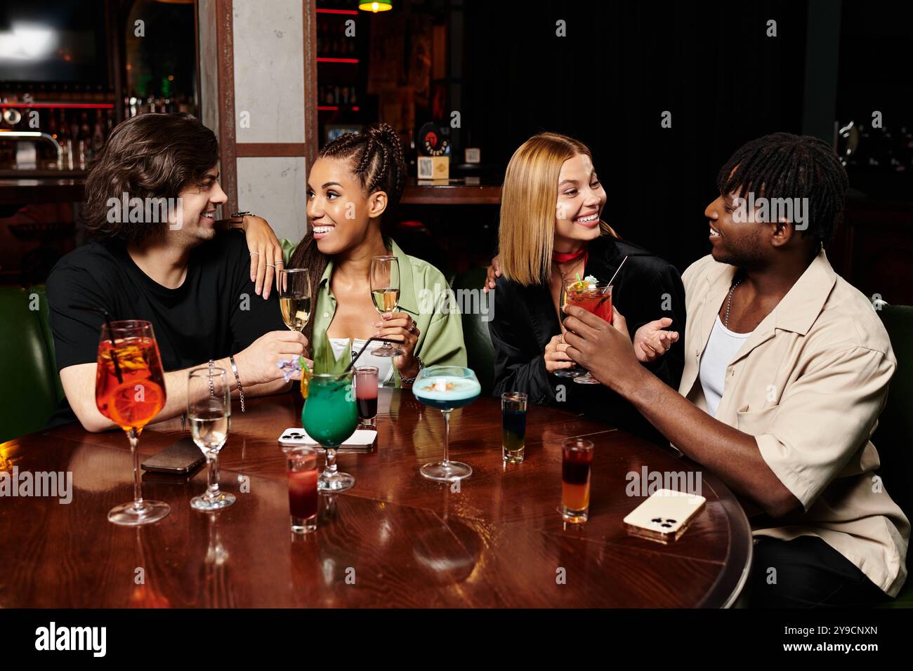 Group of young professionals laughing and toasting with colorful drinks ...