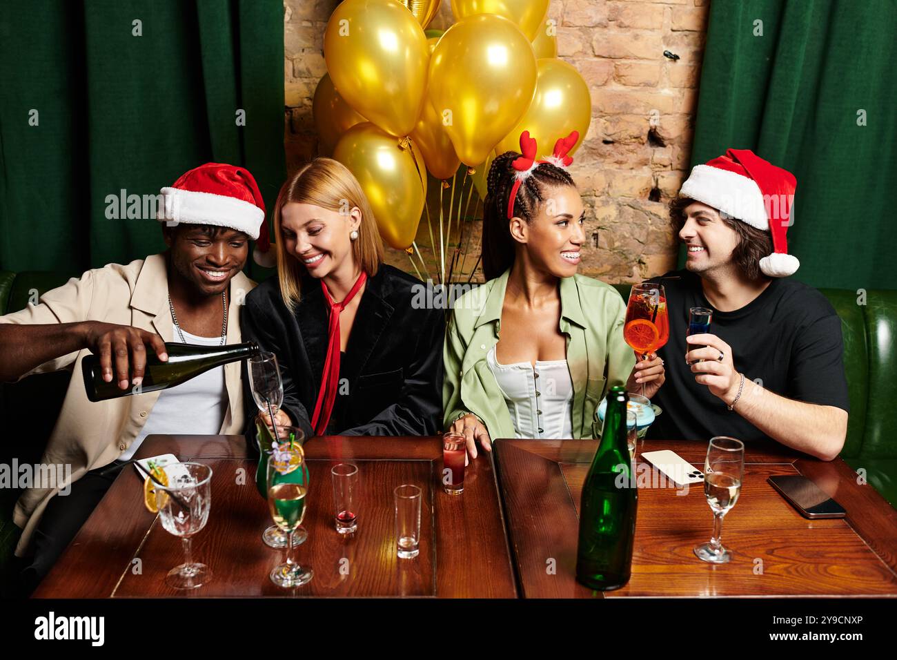 Four young professionals share laughter and festive drinks, celebrating ...