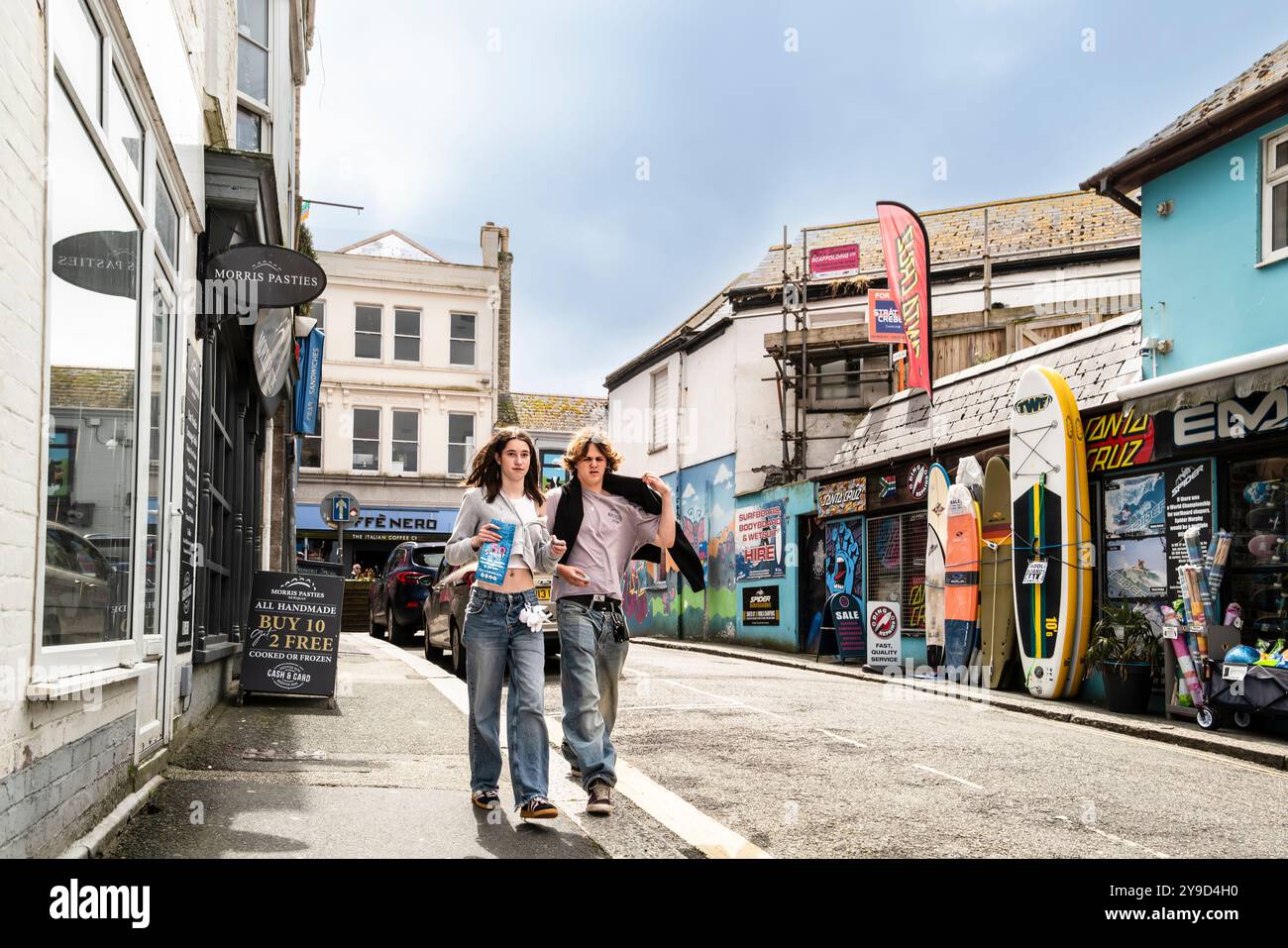 A young couple walking along a street in Newquay Town centre in ...