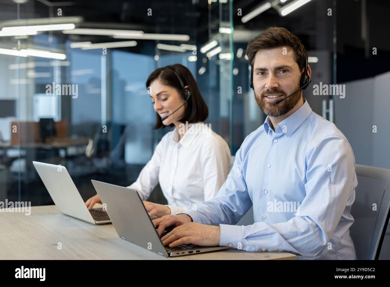 Customer service representatives using headsets and laptops in office ...