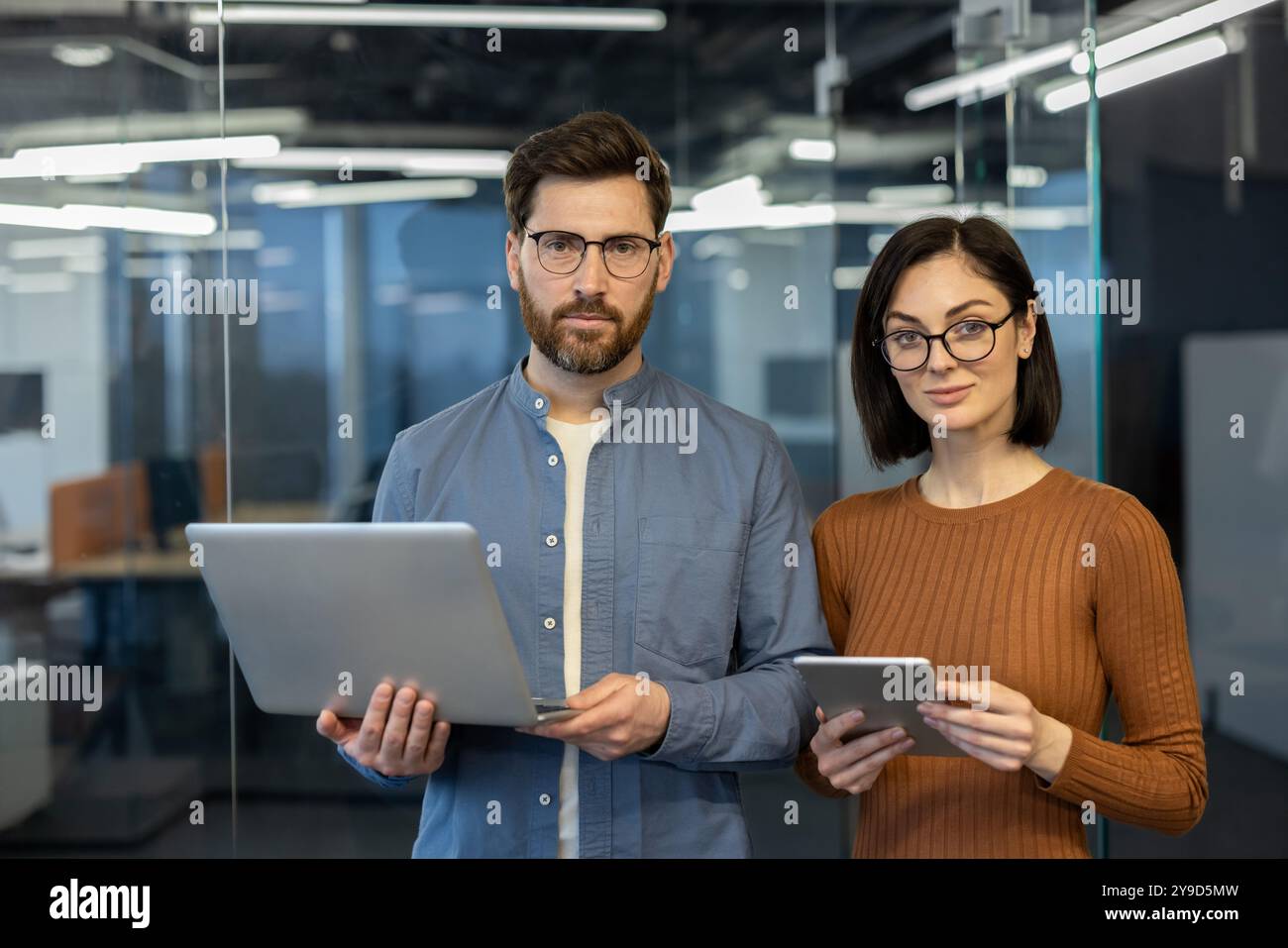 Confident business professionals in modern office environment holding ...