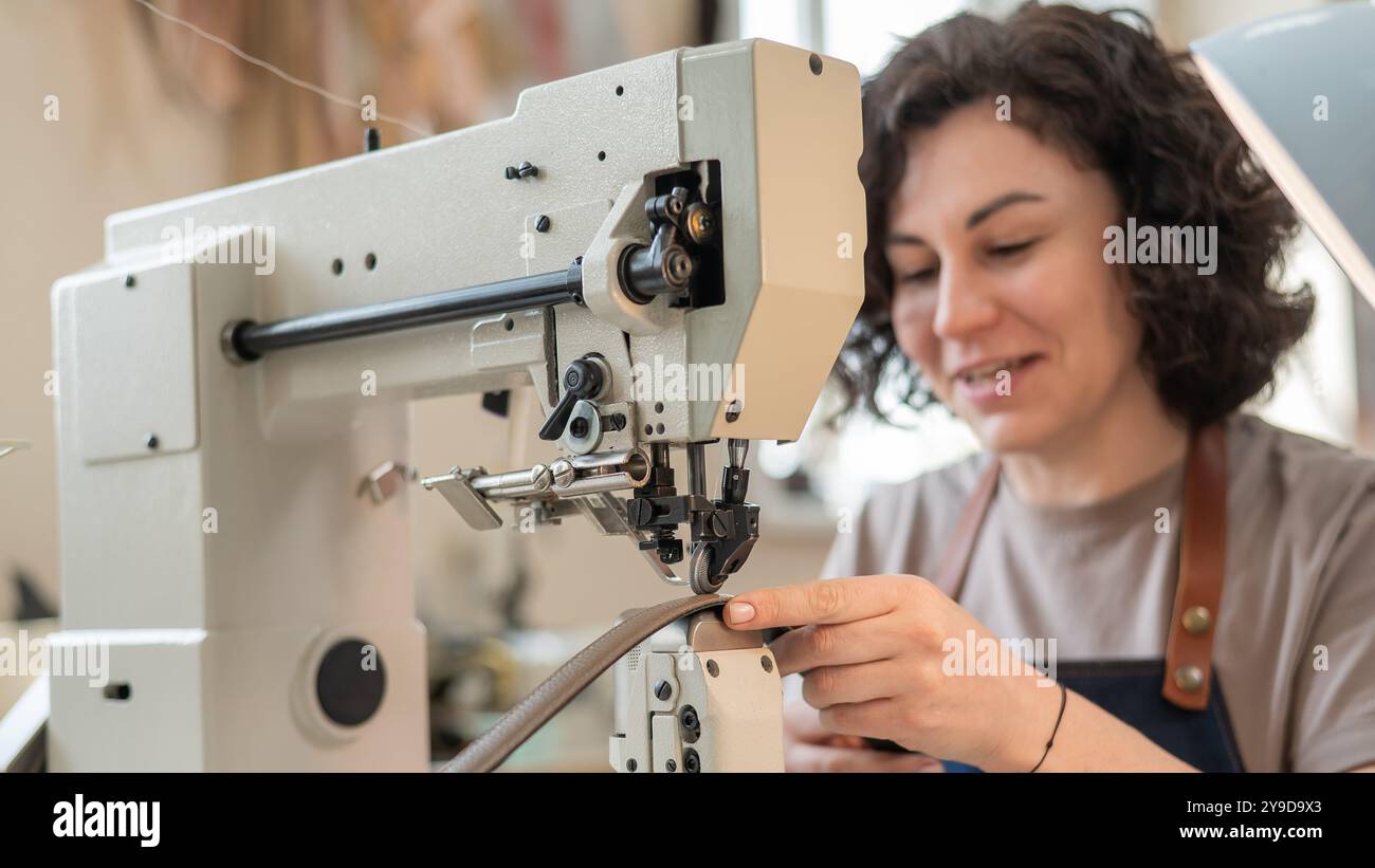 A woman tanner sews a leather belt on a sewing machine Stock Photo - Alamy