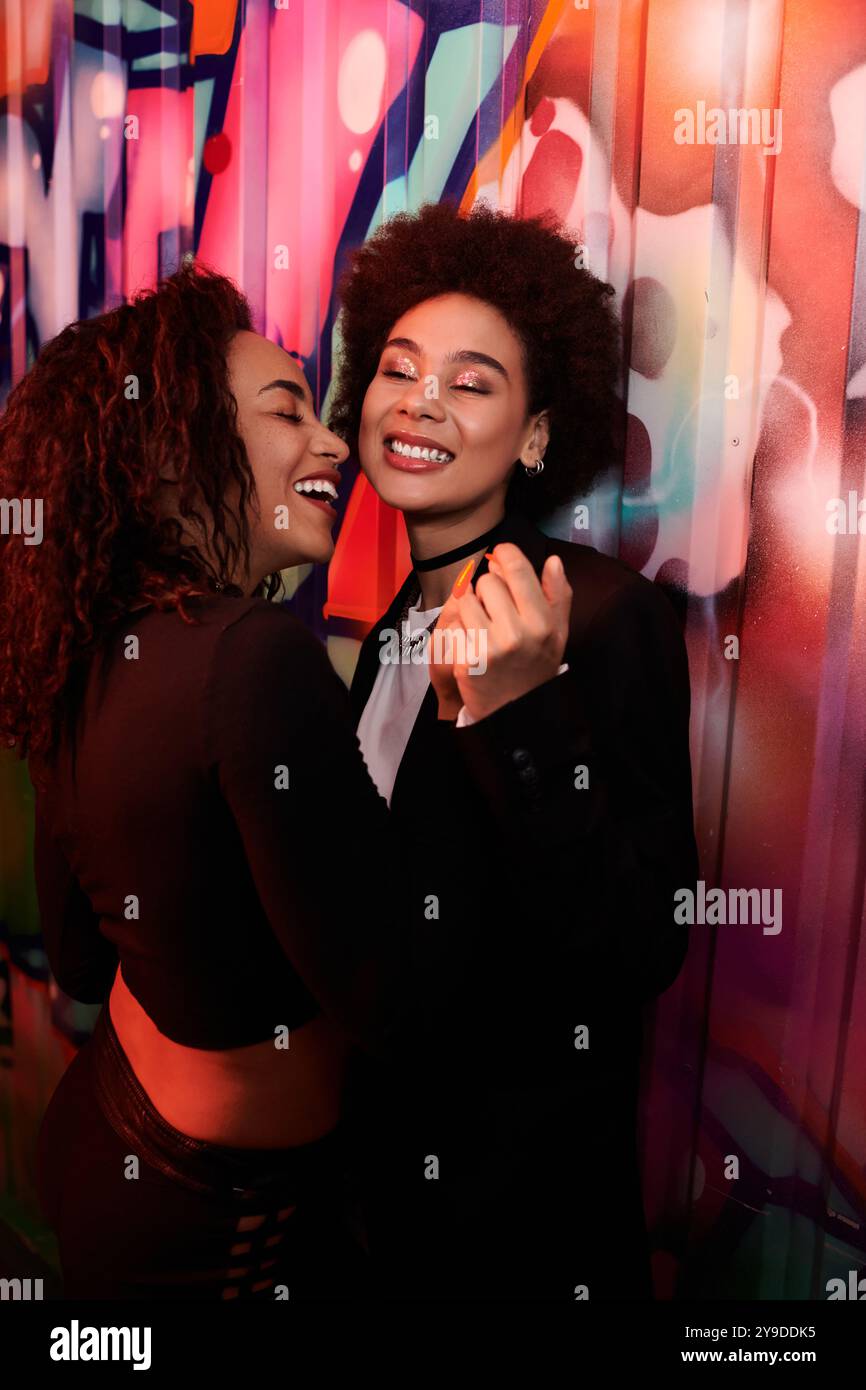 Two friends laugh and embrace, surrounded by colorful street art in an ...