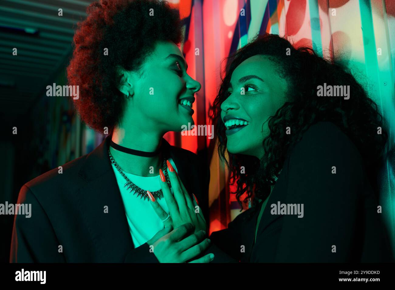 Two friends laugh and connect in a lively, artistic environment full of ...