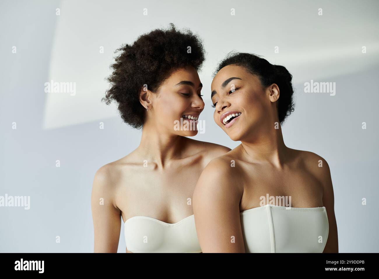 Two friends share a joyful moment, smiling and embracing in a minimally ...