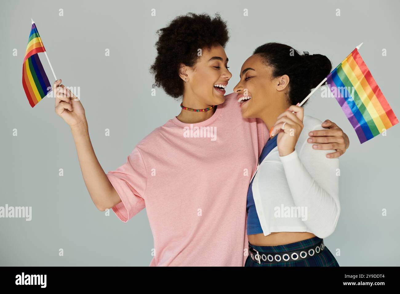 Two friends share a heartfelt moment while proudly waving rainbow flags ...