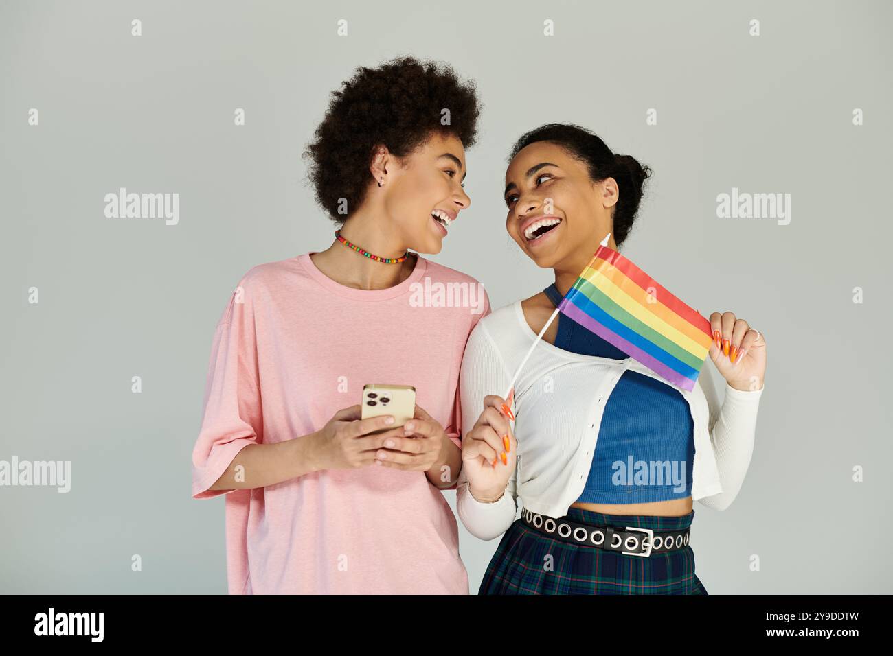 Two friends share a joyful moment, embracing their pride with a rainbow ...