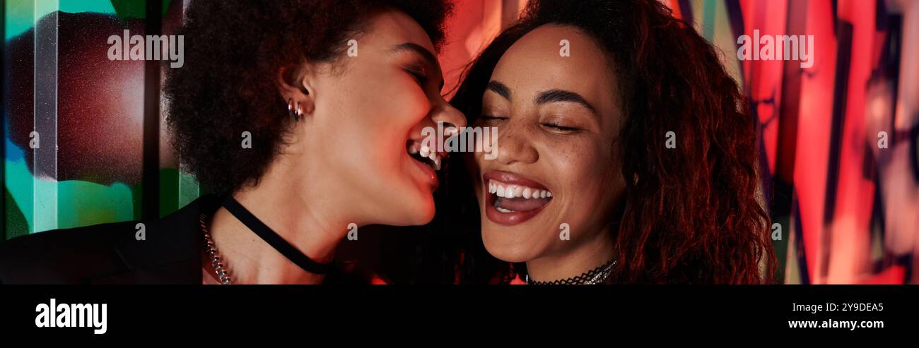 Two young women enjoy a moment of connection and laughter against a ...