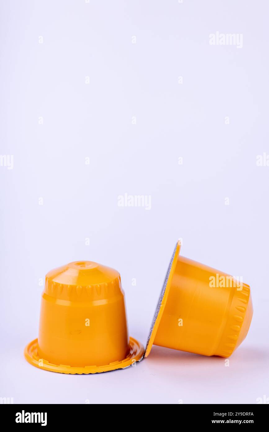 A set of yellow coffee capsules arranged on a white surface. Their ...