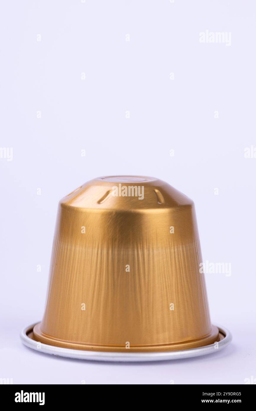 An exquisite golden coffee capsule rests on a bright white background ...