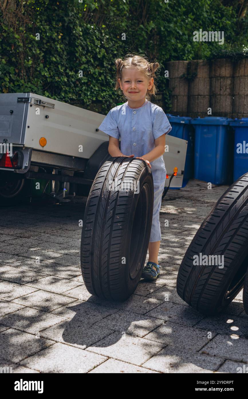 Cute little girl helps her father to change wheel on their family car ...
