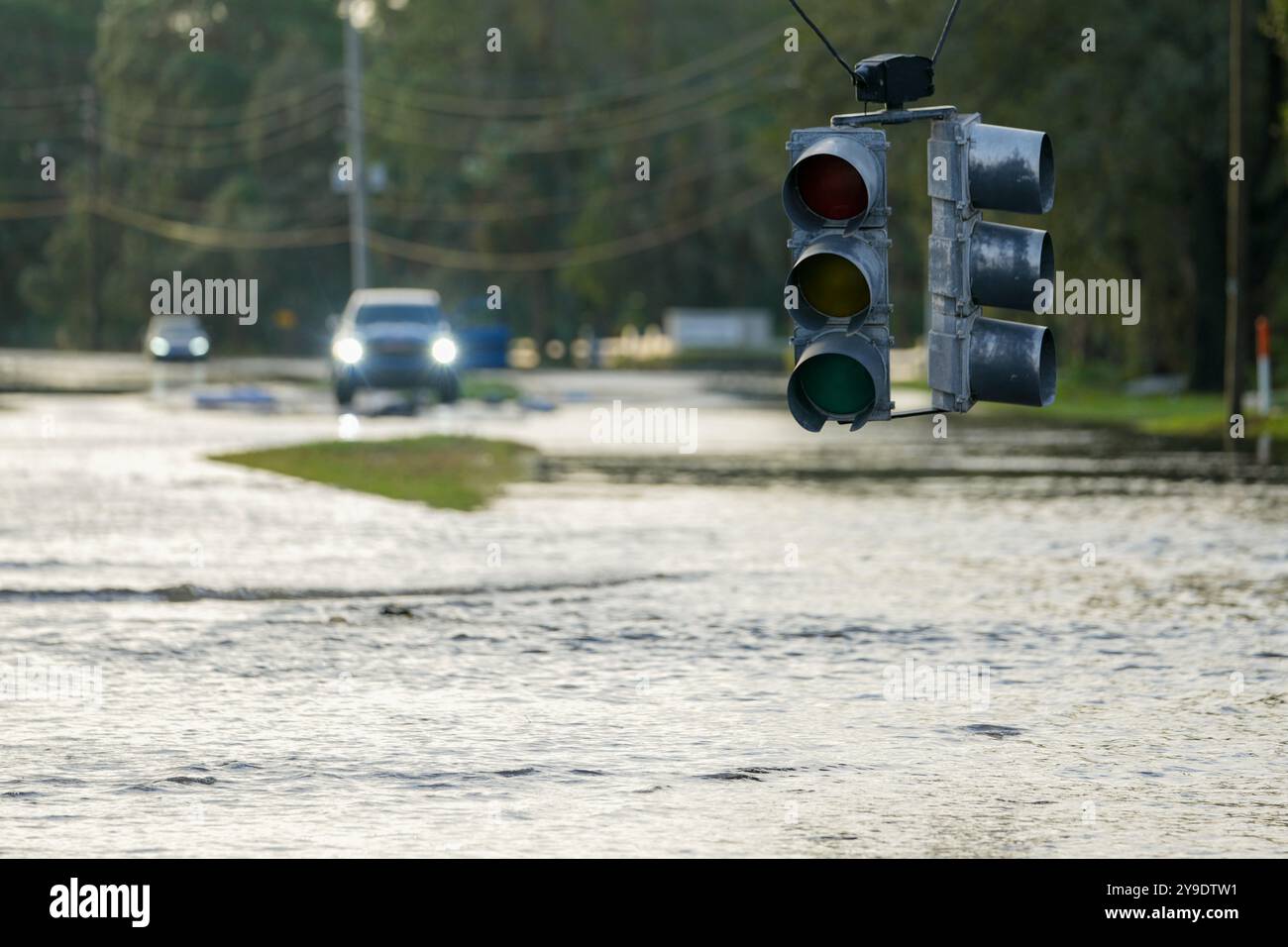 A traffic light hangs low as flood waters cover a road the morning ...