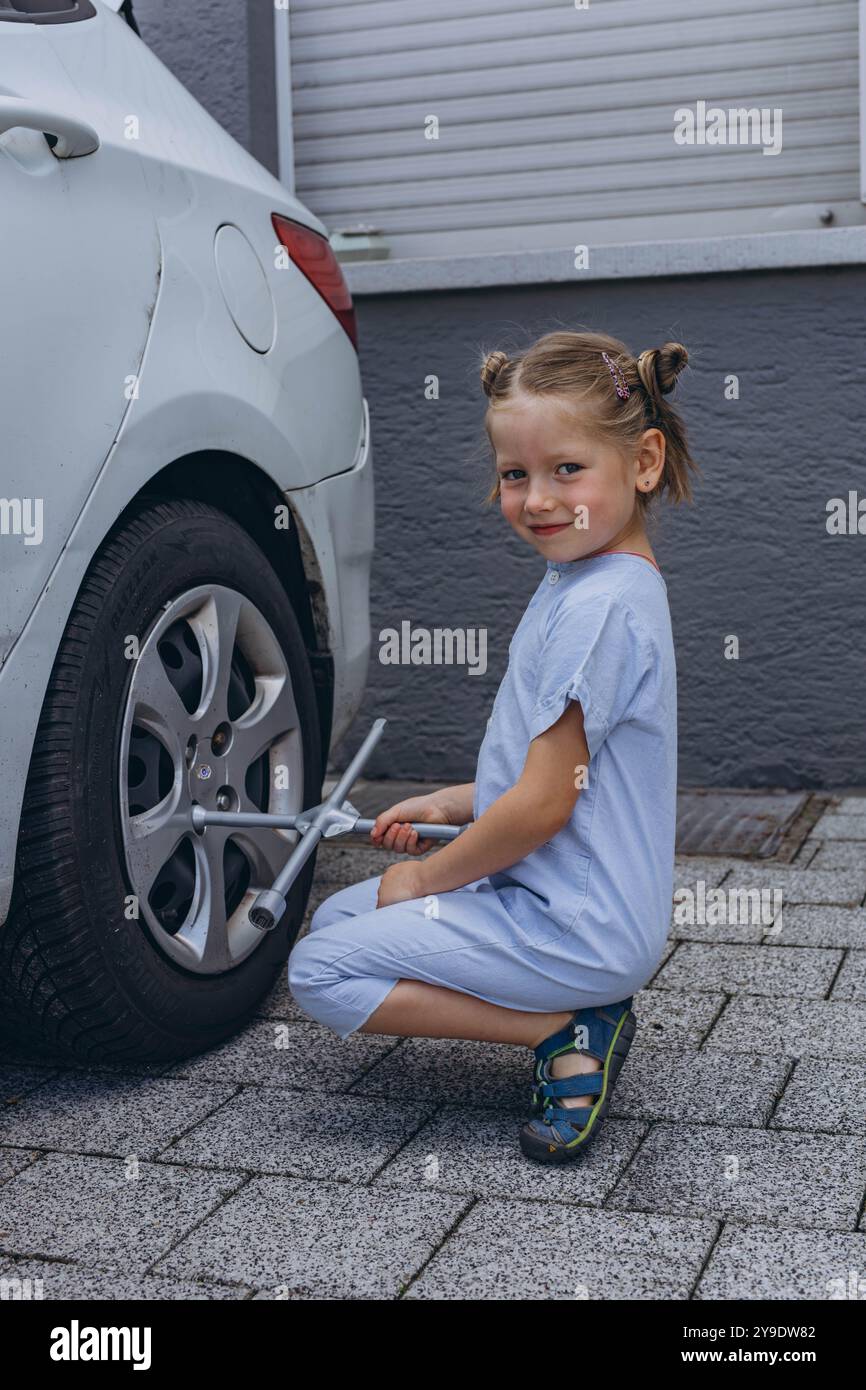 Cute little girl helps her father to change wheel on their family car ...
