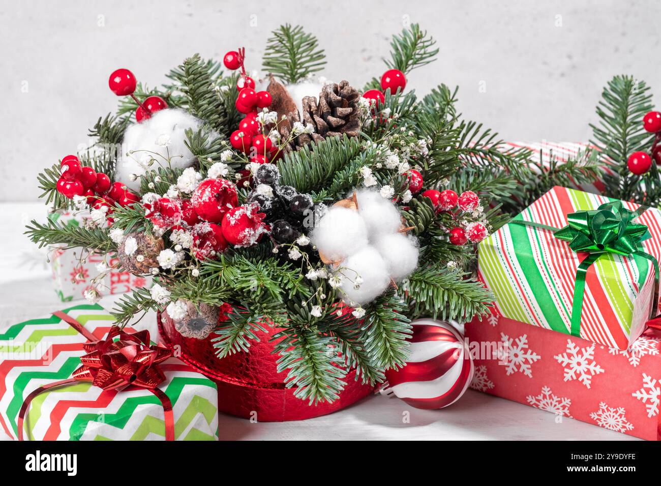 A red box with white flowers and pine cones inside. The box is placed ...