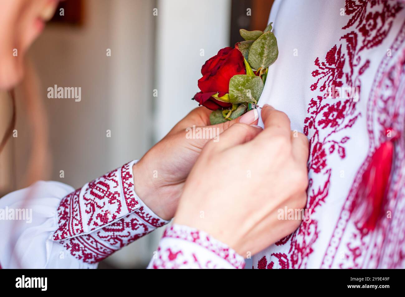Attaching a Red Rose Boutonniere to Traditional Embroidered Shirt Stock ...
