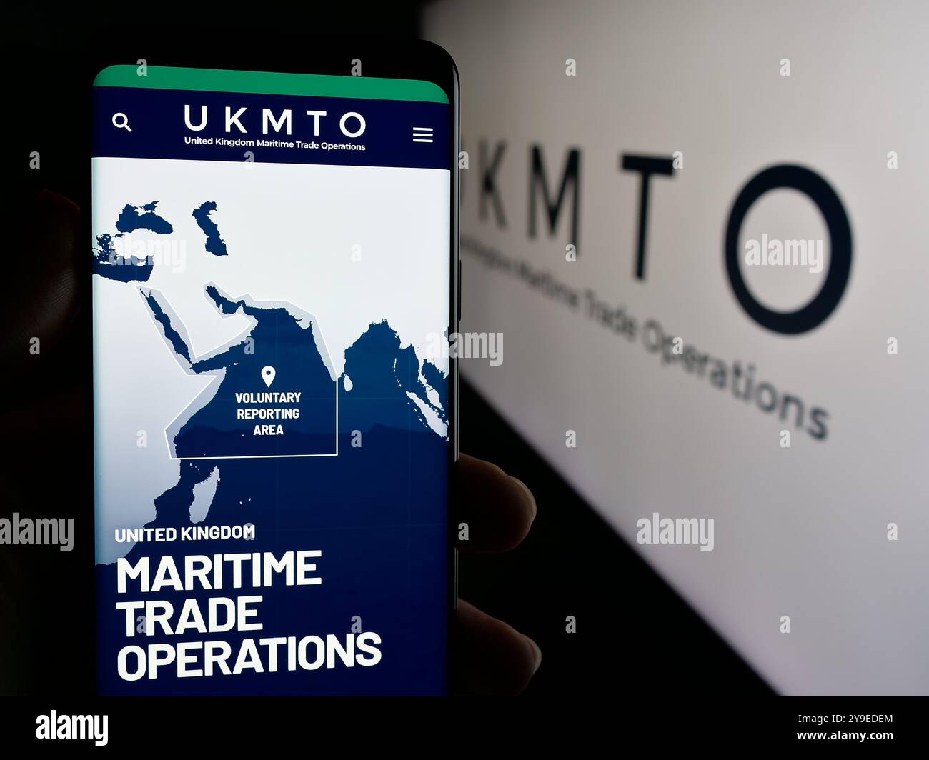 Person holding cellphone with webpage of United Kingdom Maritime Trade ...