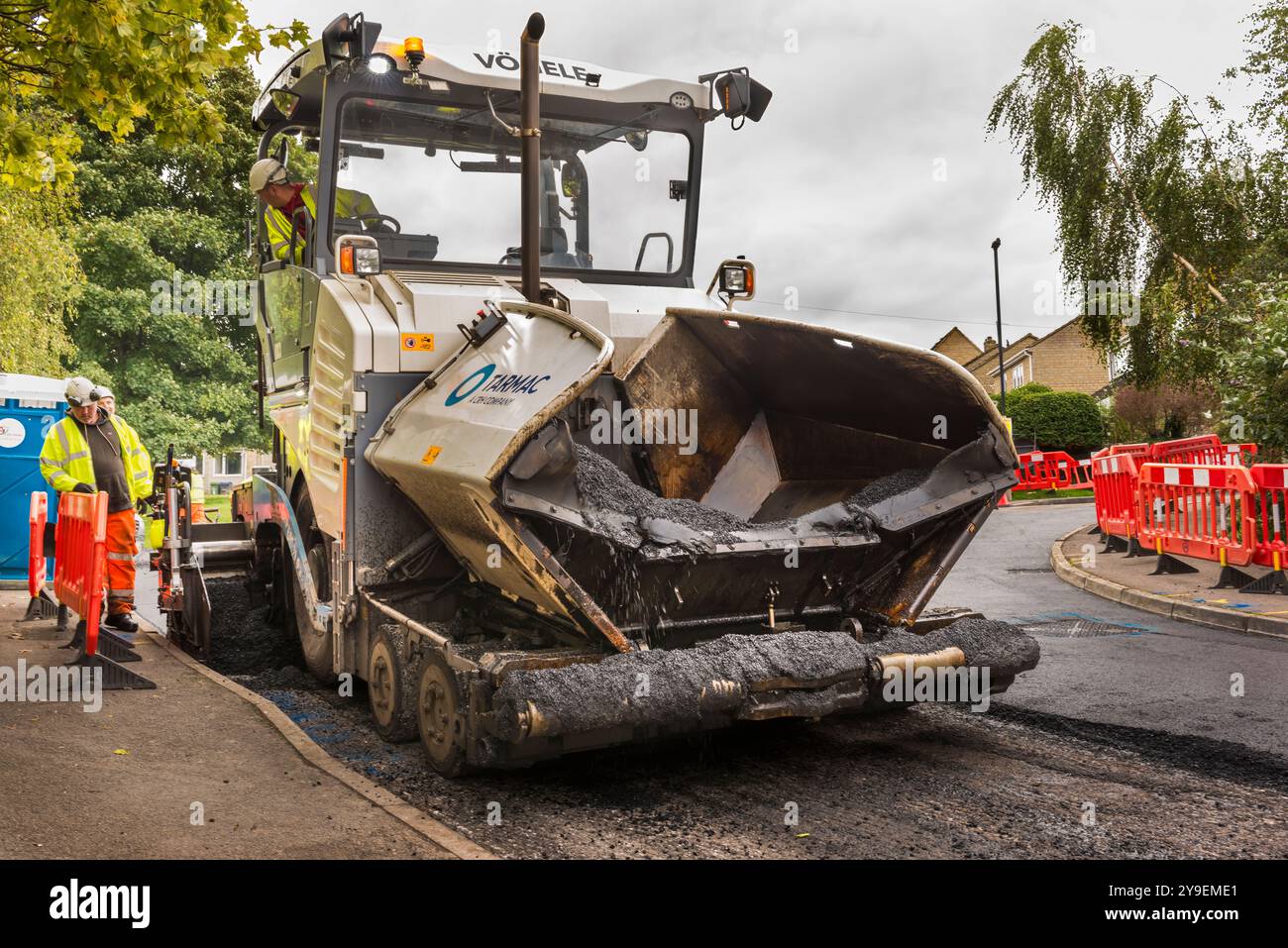 A team of workman operating heavy machinery to resurface a residential ...