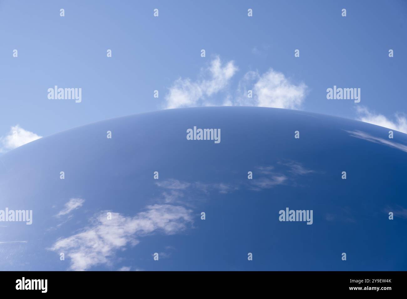 A shiny, reflective surface captures the sky, blending with scattered ...