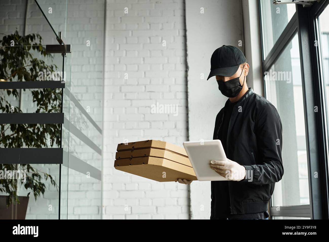 A delivery professional in a black mask carries food boxes into a ...