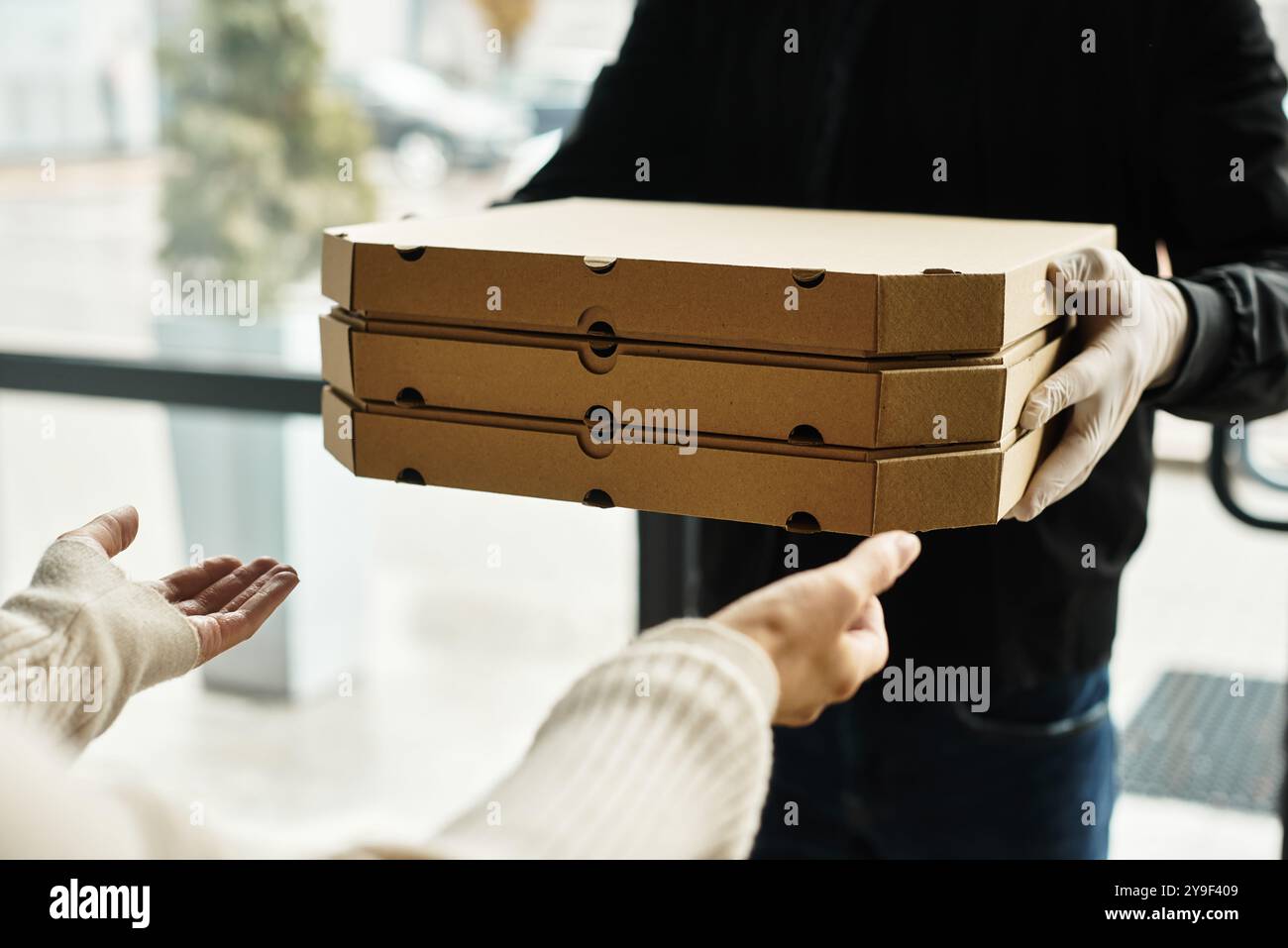 A delivery person hands over several food boxes in a bustling office ...