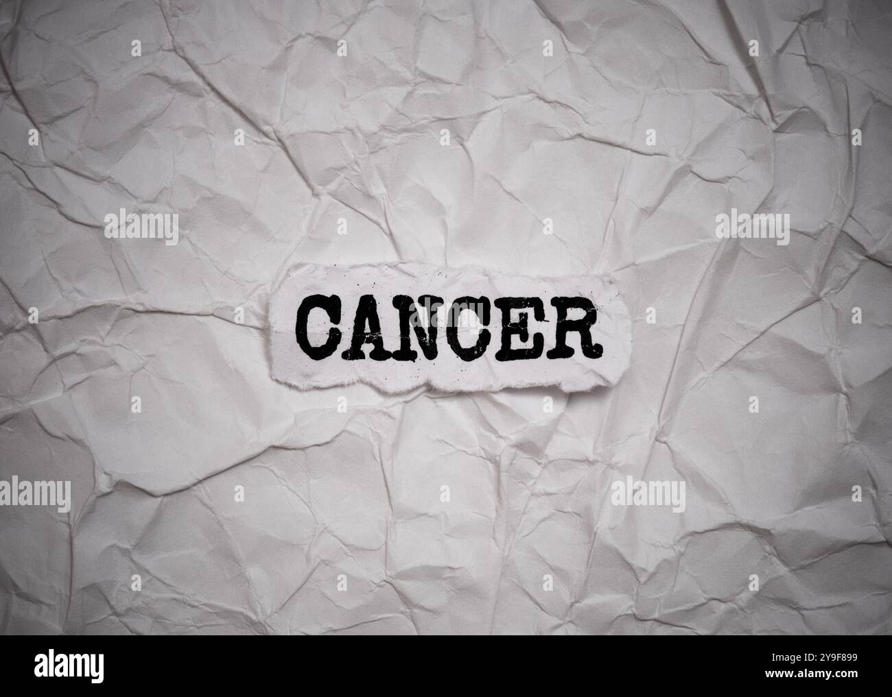 Crumpled piece of paper with word Cancer on a crumpled paper background ...