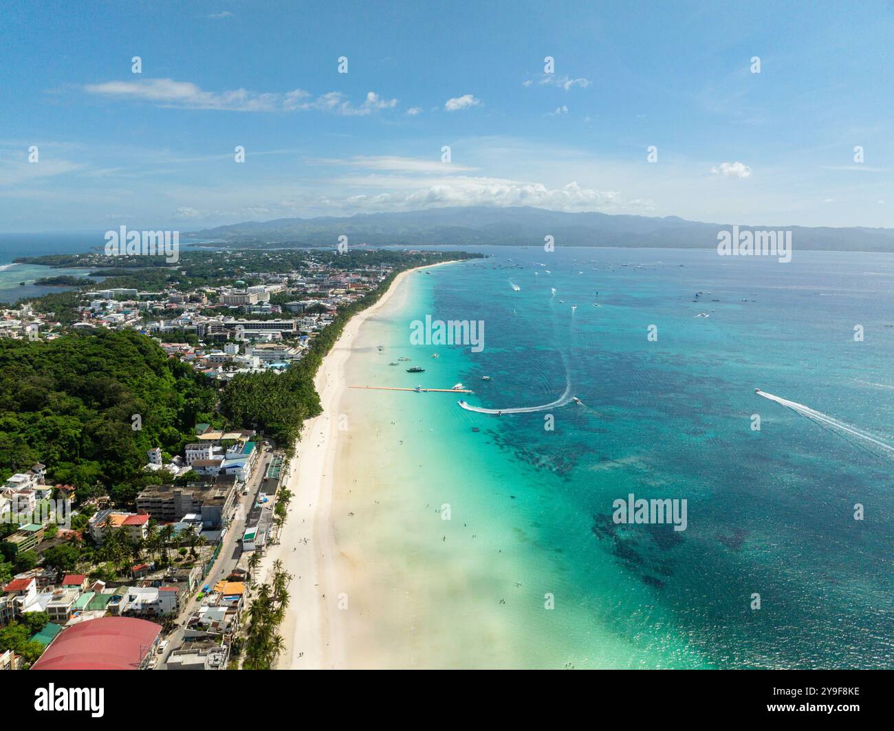 Tropical white sand beach with waves and boats over clear waters ...