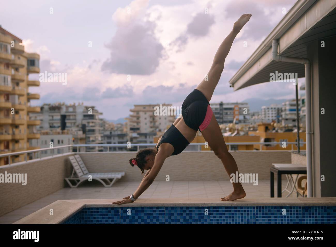 Engaging in a Dynamic Yoga Pose at a Rooftop Pool Offering Stunning ...