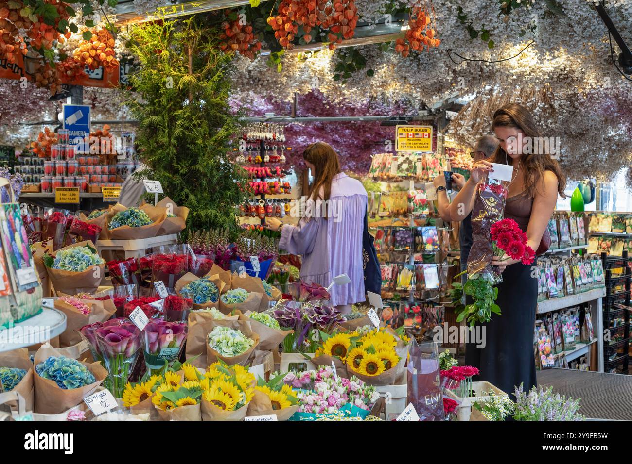 Tourists view the flowers in a flower stall at the floating flower market in Amsterdam Stock ...