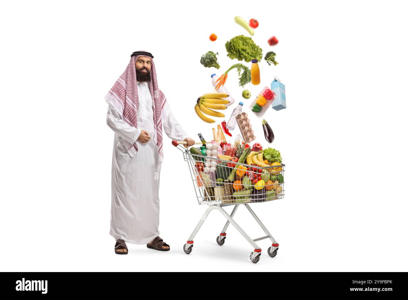 Arab man standing with a shopping cart full of food products and ...