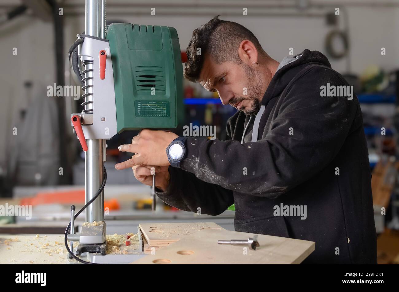 Man repairing machinery in his workshop, with an automatic table drill ...