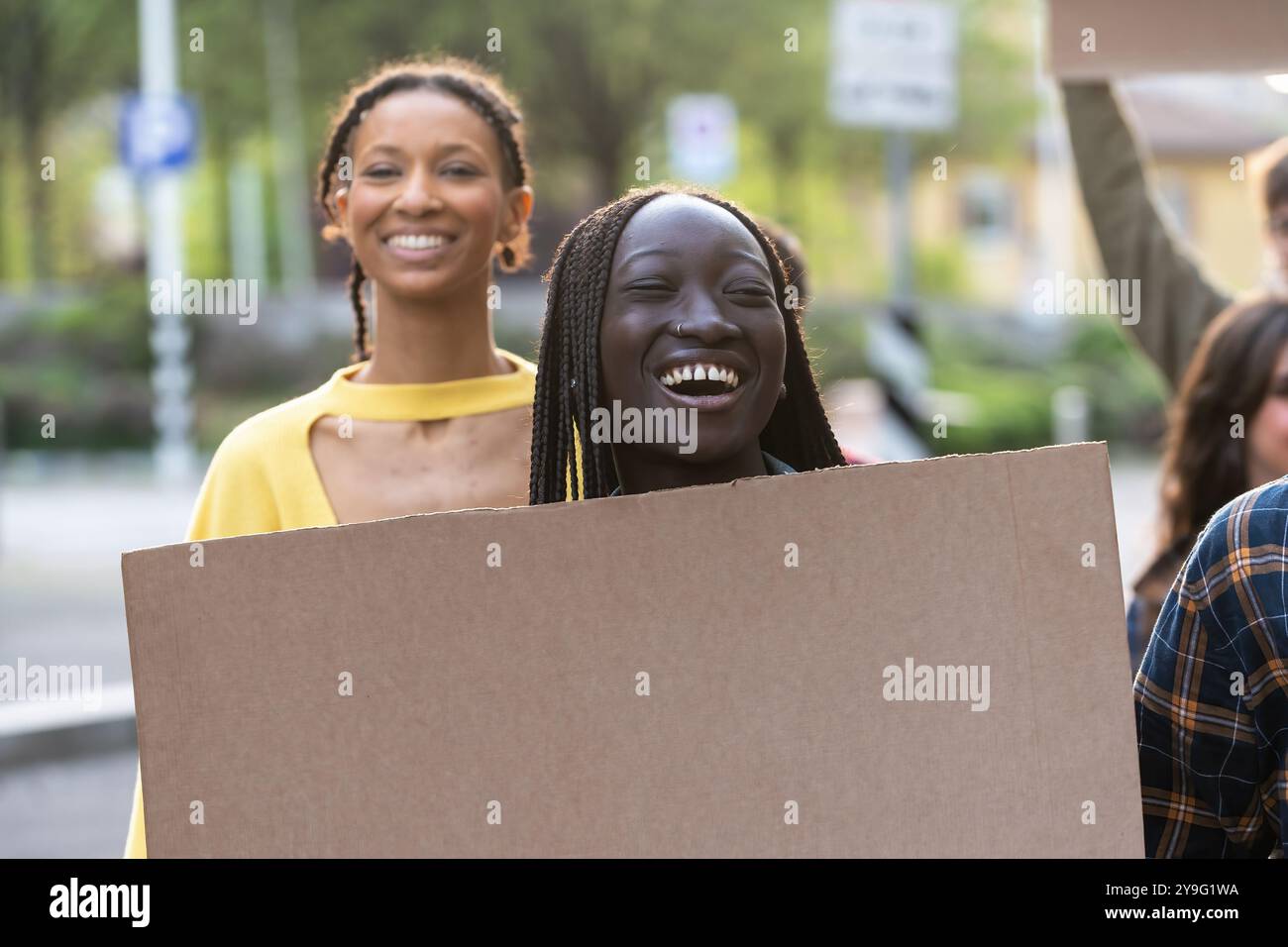 Two joyful African women at outdoor protest, one holding blank ...