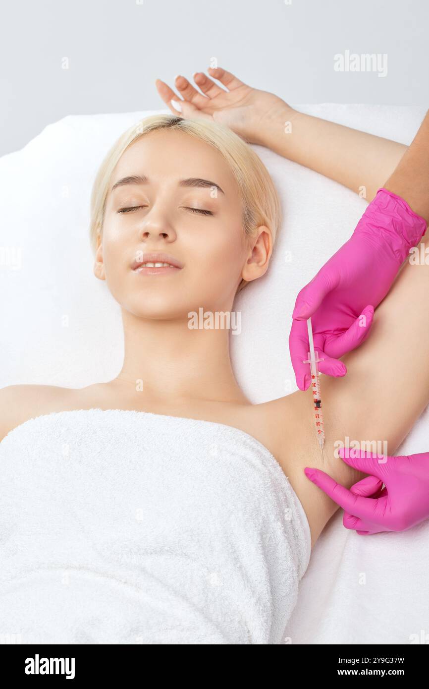 The doctor makes injections of botulinum toxin in the underarm area ...
