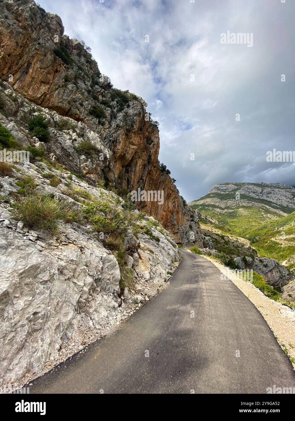 Winding road cuts through a steep mountain landscape, framed by ...