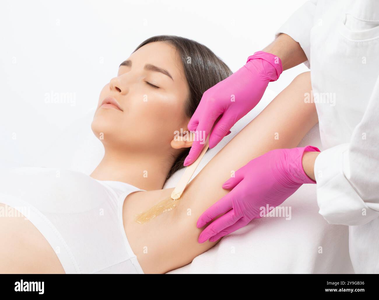 A beautician makes a sugar paste depilation under the armpits in a ...