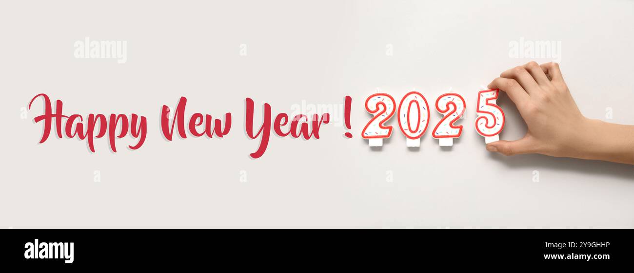 Female hand with candles in shape of figure 2025 and text HAPPY NEW ...