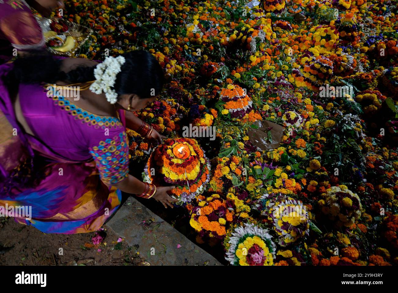 A Hindu devotee performs ritual with Bathukamma, floral arrangement ...