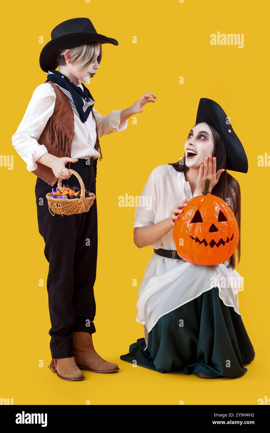 little boy with candies and his mother dressed for Halloween on yellow ...