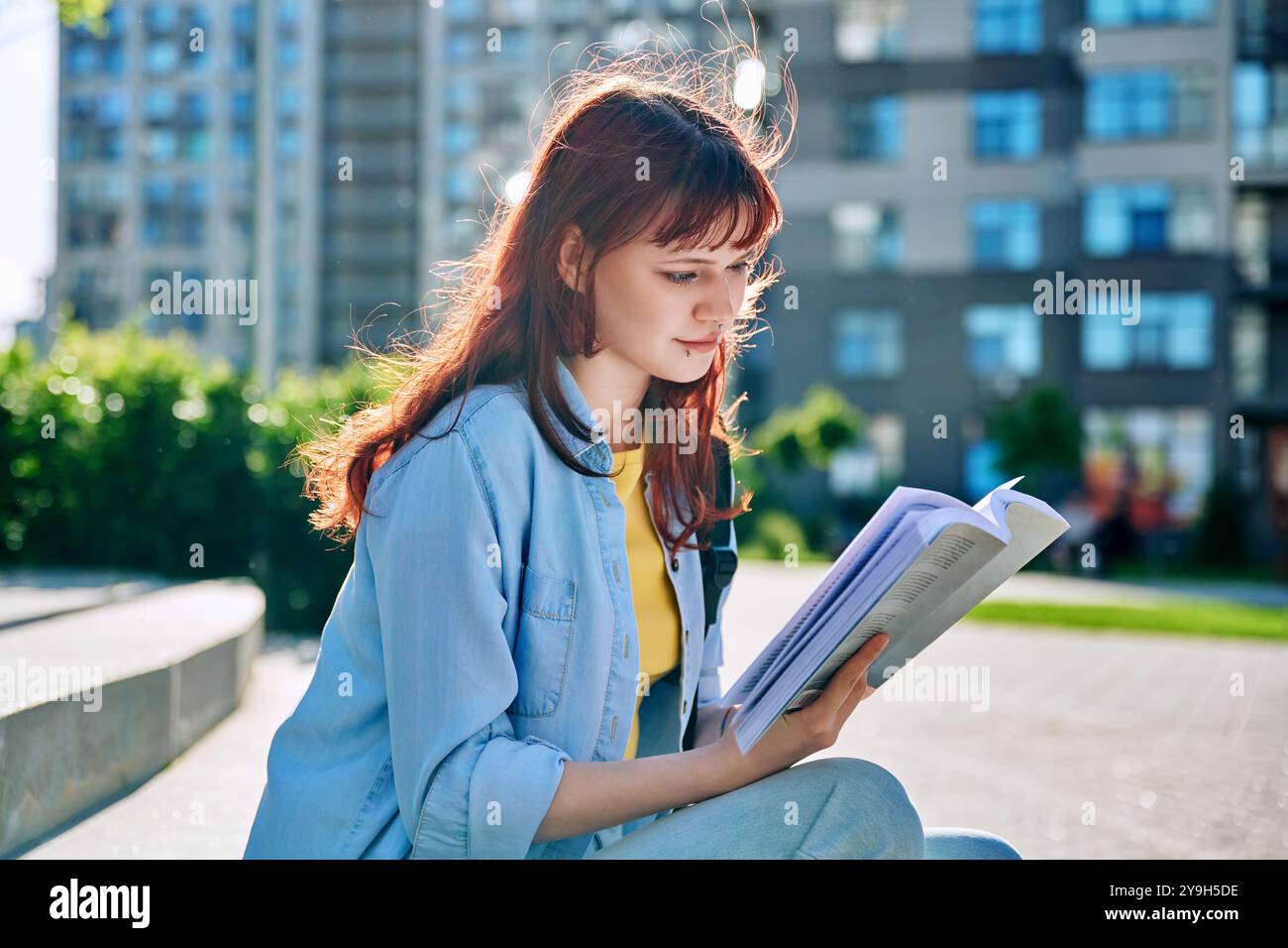 College student girl reading a book, outdoor Stock Photo - Alamy