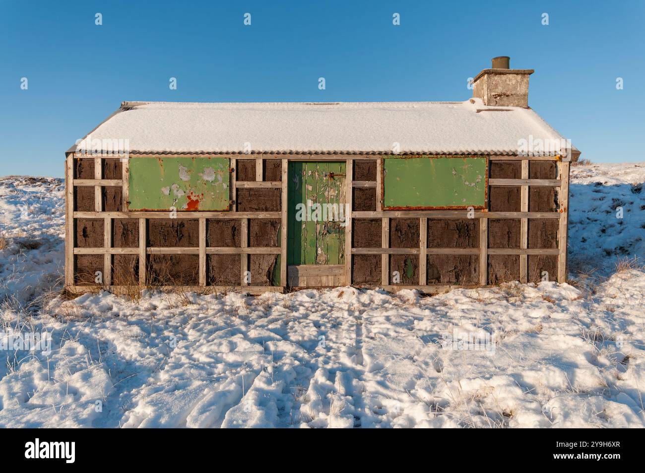 An abandoned, dilapidated shieling sits on a snow-covered landscape ...