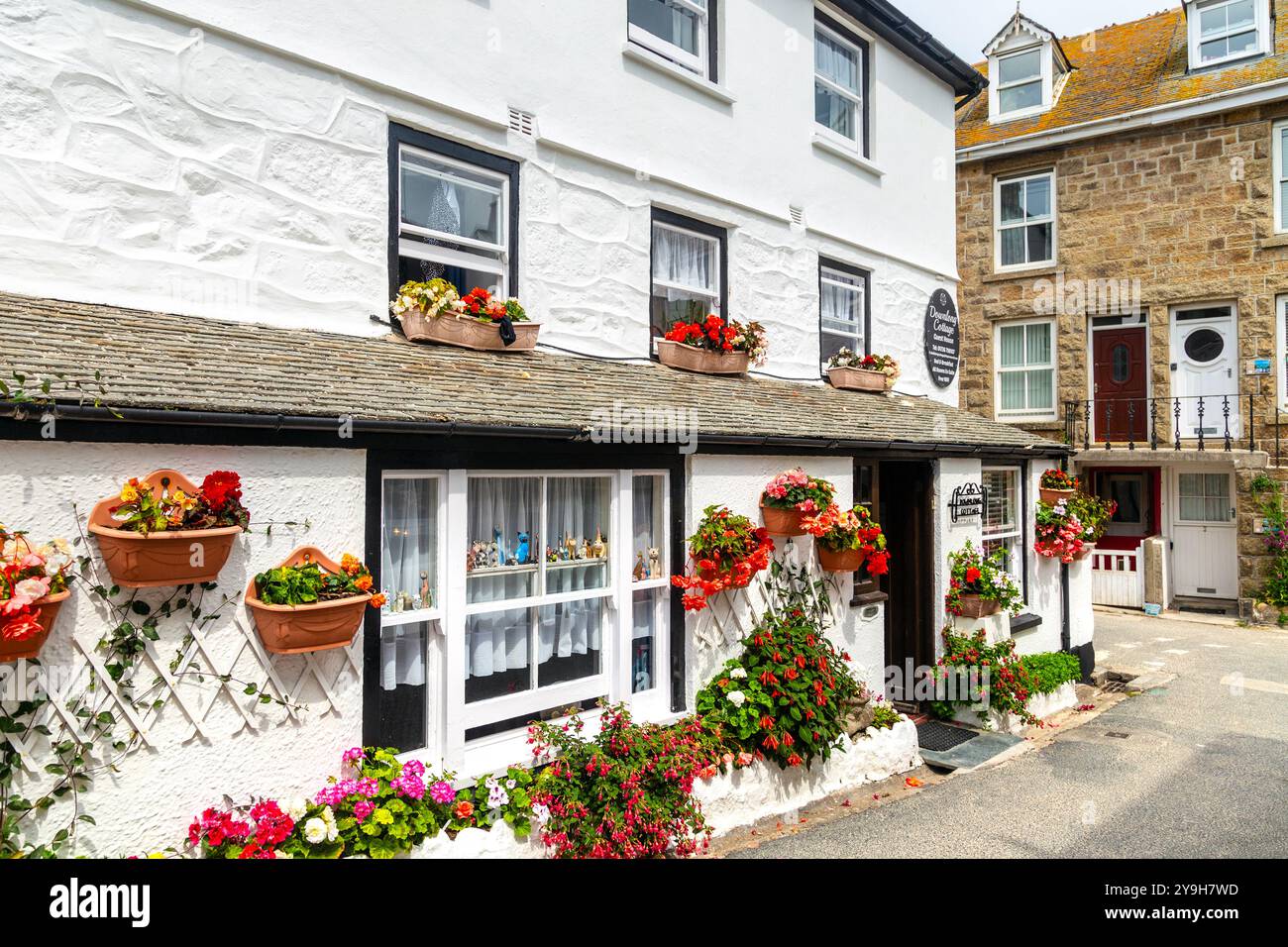 Exterior of a white cottage decorated with red flowers (Downlong ...