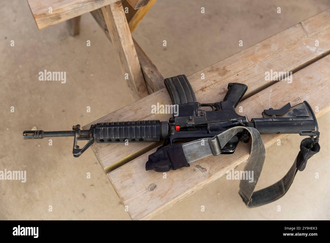 A military rifle rests on a wooden bench in the dining area for ...